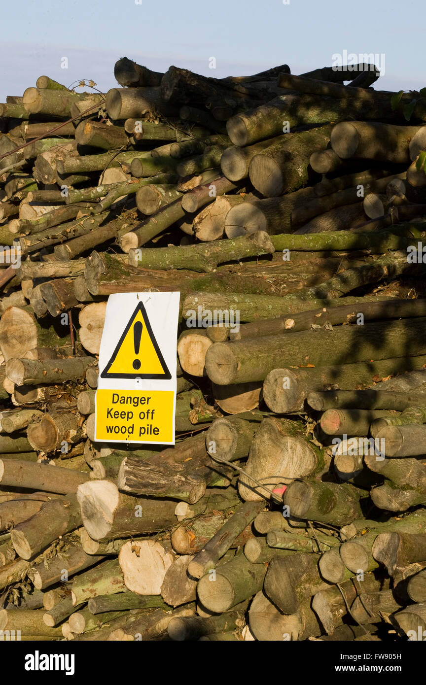 A large pile of logs with a warning sign attached asking people to keep ...