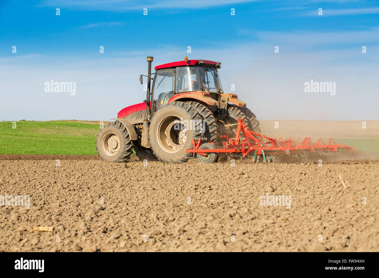Tractor cultivating field at spring Stock Photo - Alamy