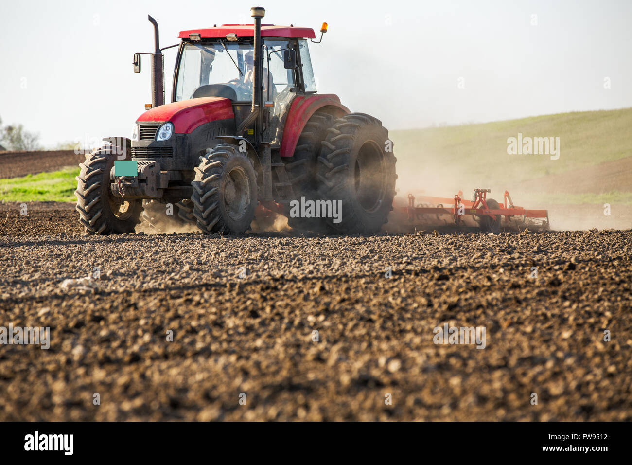 Tractor cultivating field at spring Stock Photo - Alamy