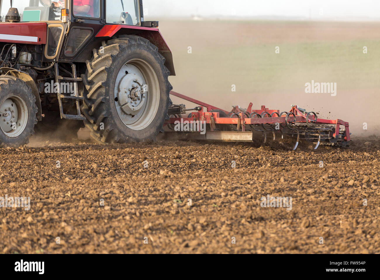 Tractor cultivating field at spring Stock Photo - Alamy