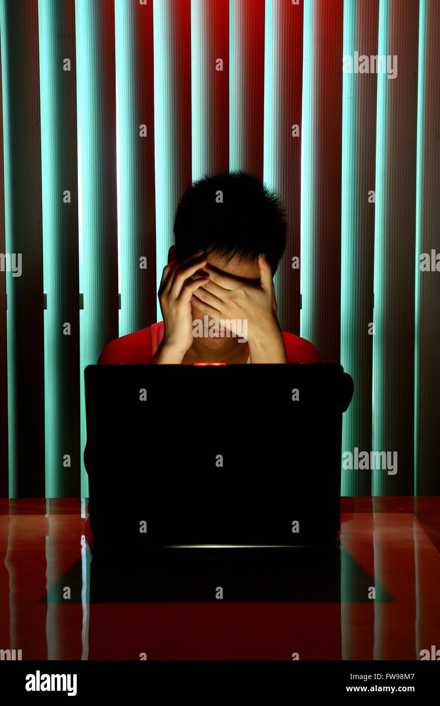 Teen in front of a laptop computer and covering his face Stock Photo ...