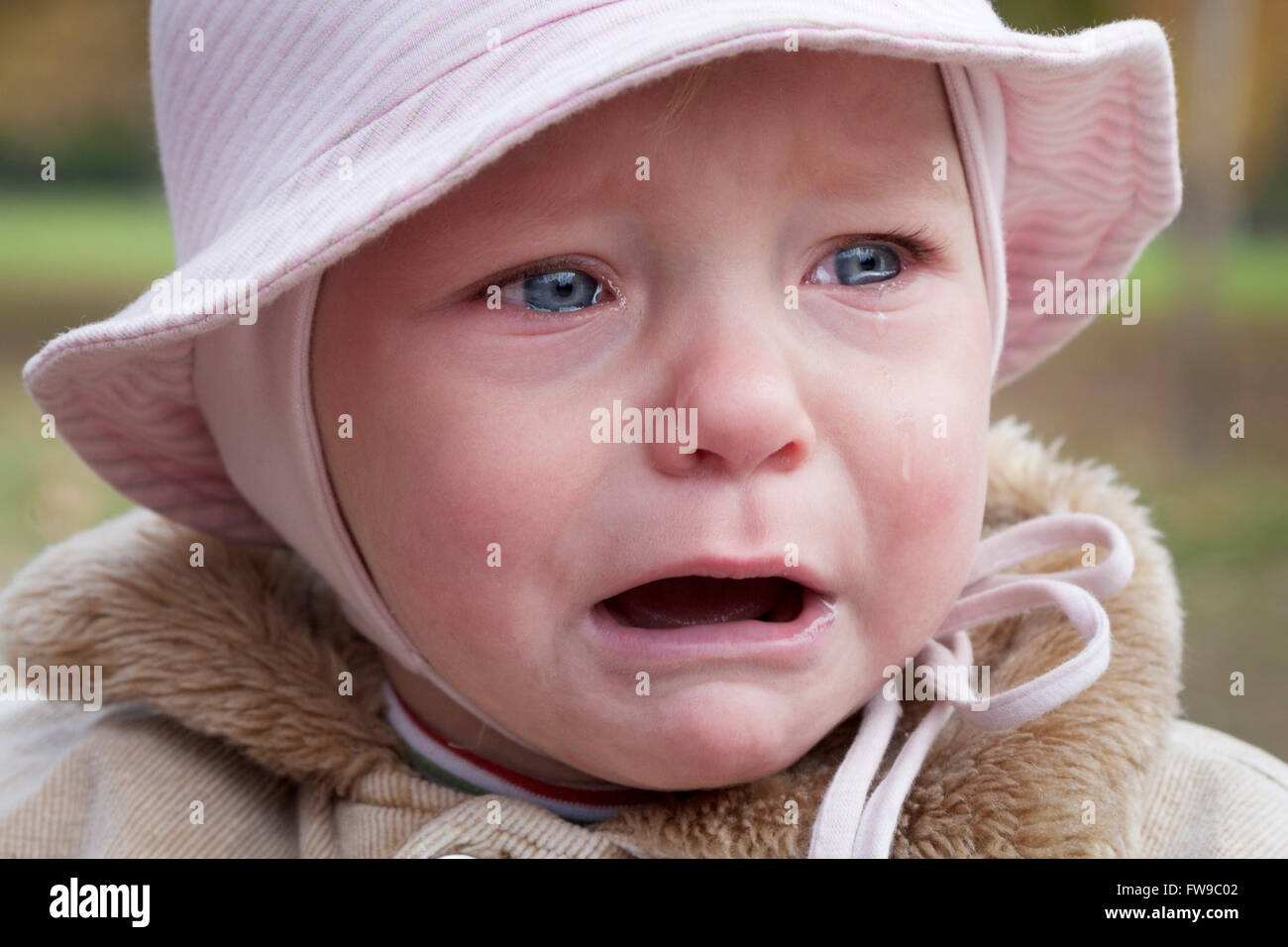 Little girl with pink cap crying Stock Photo - Alamy