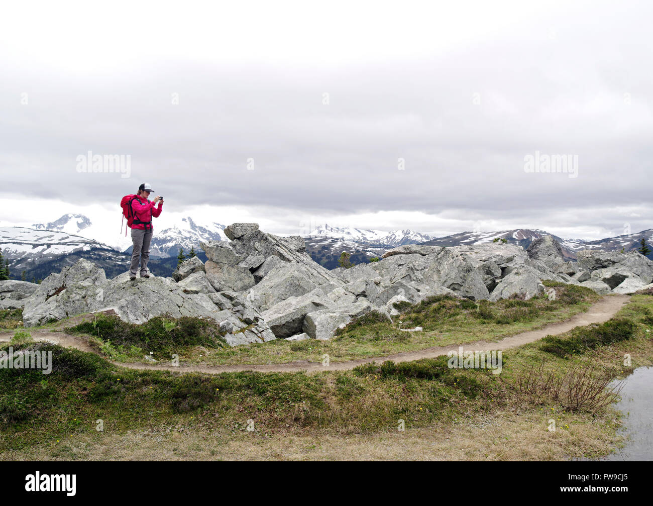 A young female hiker on mountain summit holding a smart phone in ...