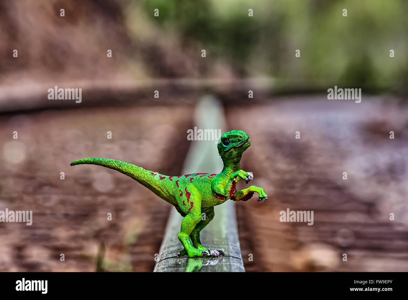 Green Velociraptor dinosaur walking on rail railroad tracks Stock Photo ...