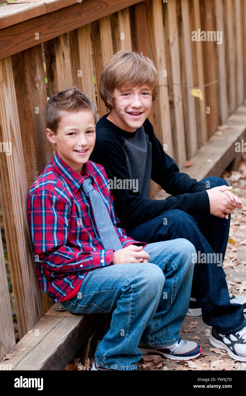 Little boys sitting side by side outdoors outdoors next to bridge Stock ...