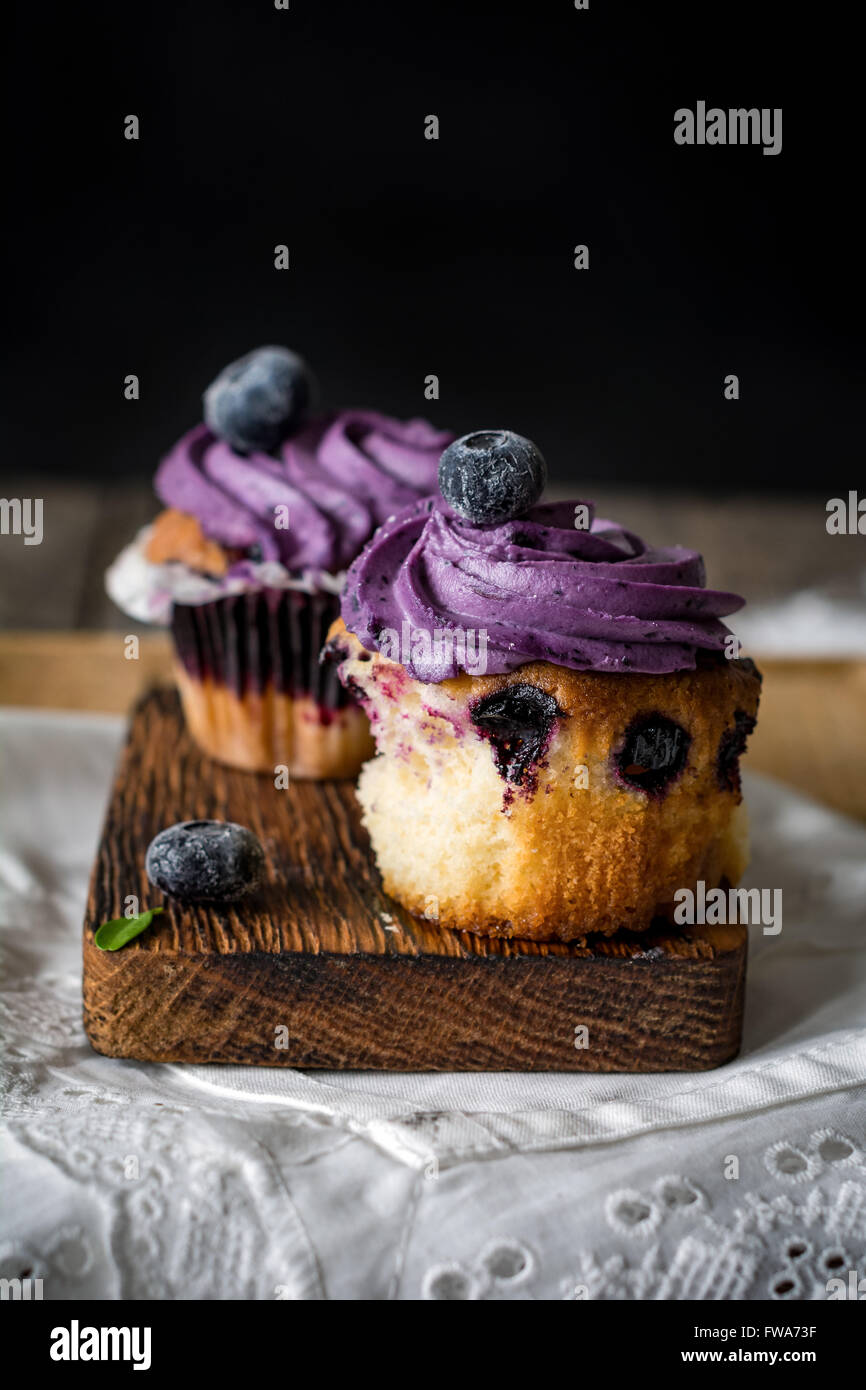 Blueberry cupcakes with purple butter cream on wooden board, close up ...