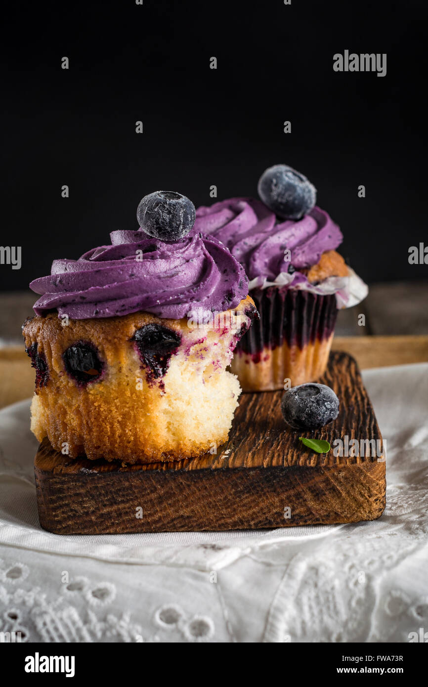 Blueberry cupcakes with purple butter cream on wooden board, close up ...