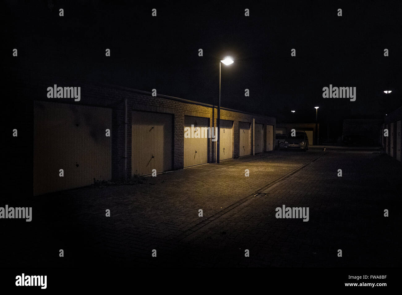 A side street in Belgium with garages for cars lit by a street light ...