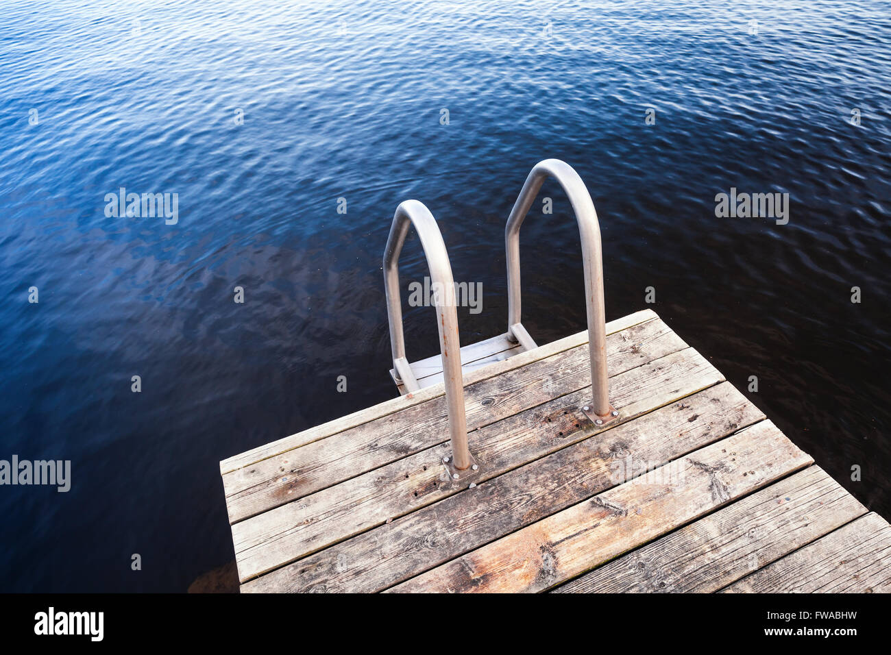 Deep blue water and wooden pier for swimming on still lake coast Stock ...