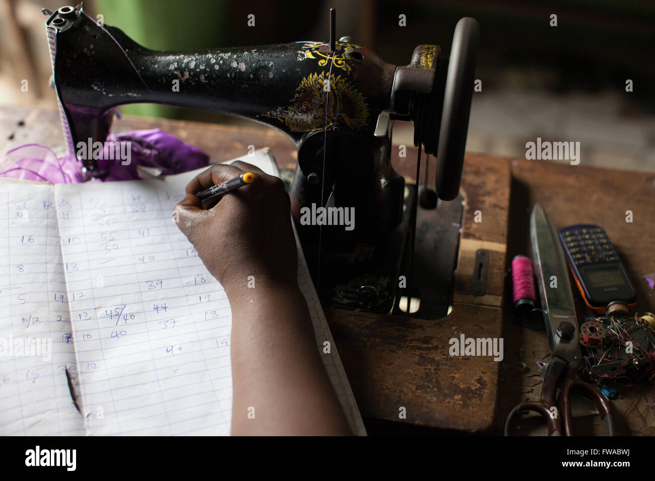 A female entrepreneur doing her bookkeeping for her dressmaking ...