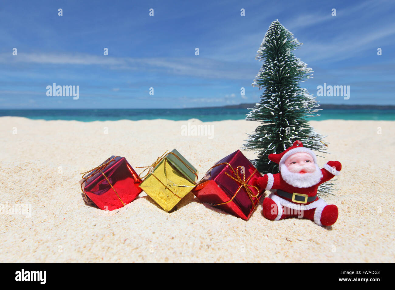 Santa Claus with fir tree and gifts on sand at tropical ocean beach ...
