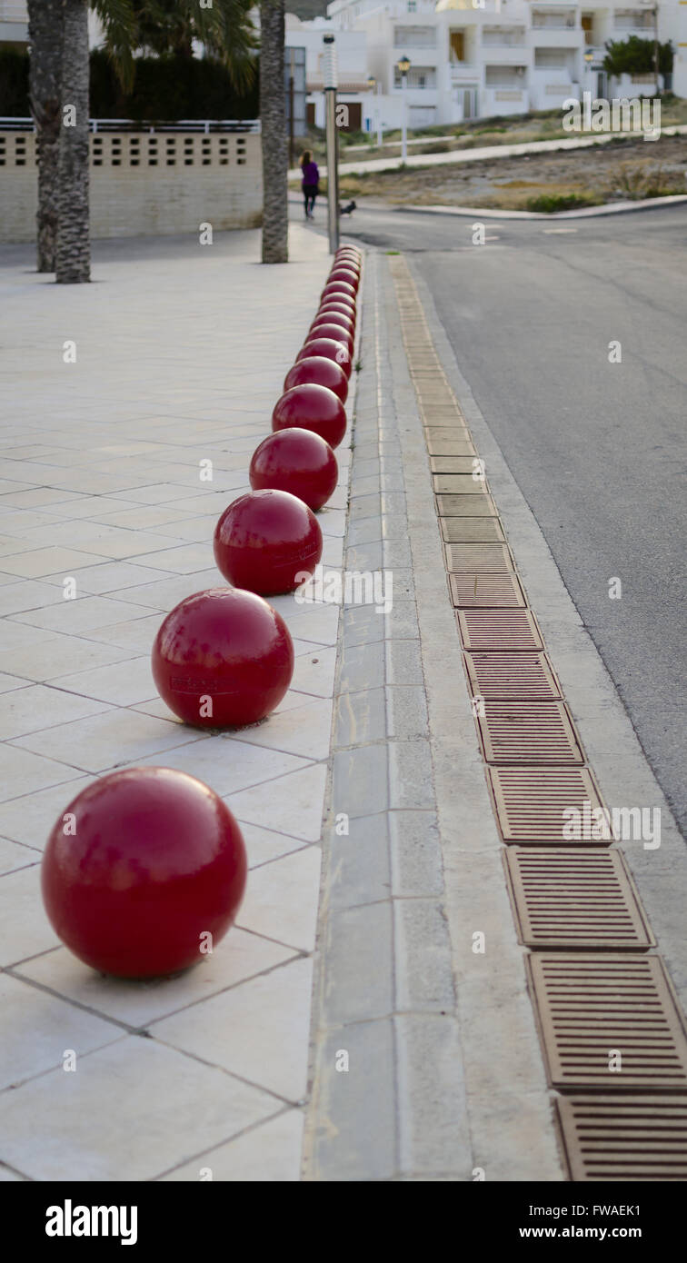 A red metal ball line in a street of Carboneras village, Almeria, Spain ...