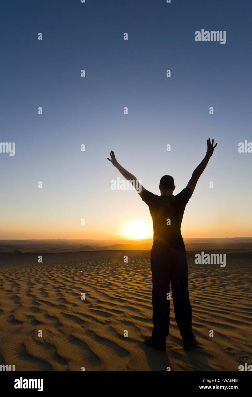 standing man with hands up at sunset in desert with shining sun Stock ...