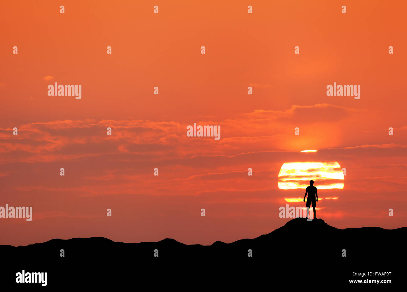 Sunset landscape with silhouette of a standing happy man against the ...