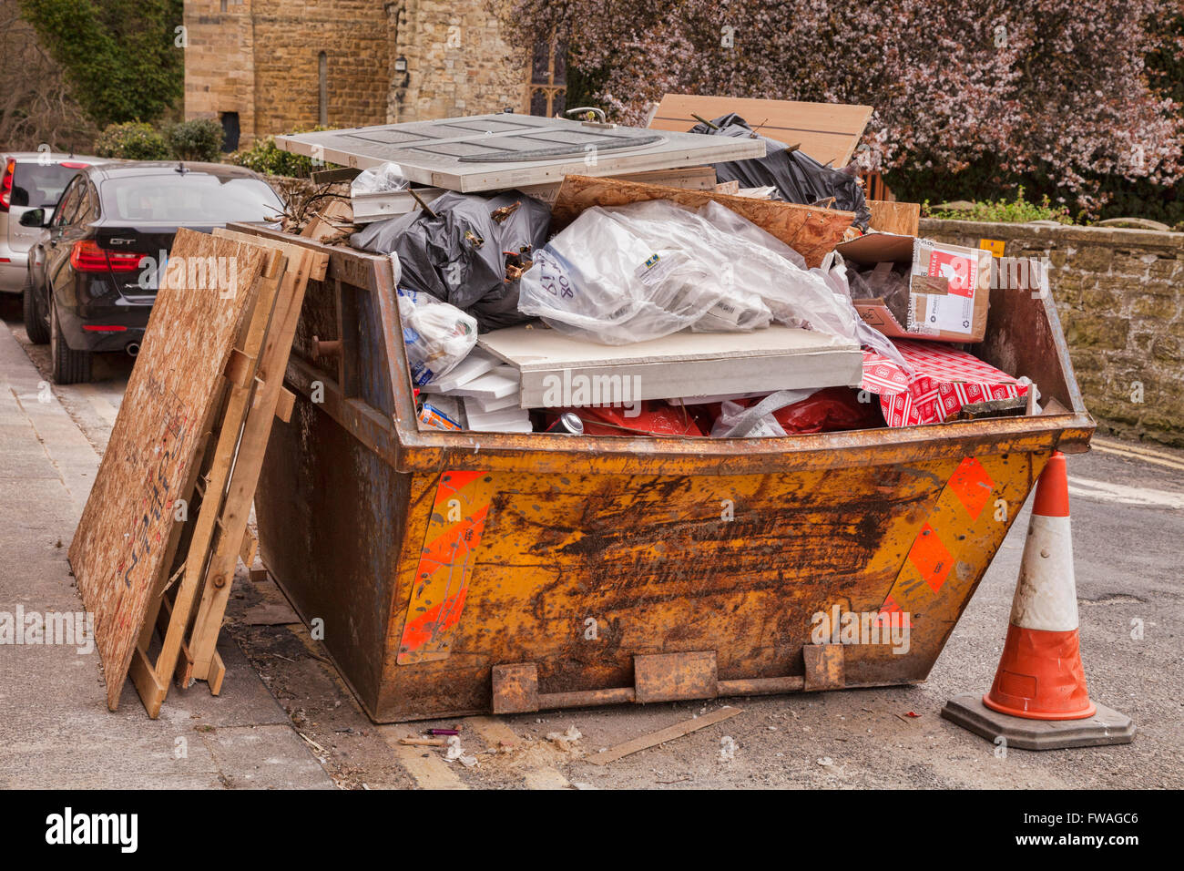 Builder's skip on the roadside, filled with rubble Stock Photo - Alamy