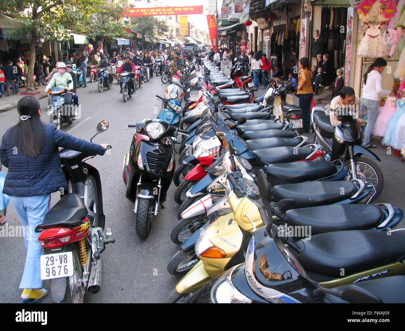 A busy street full of motorcyclists and parked motorcycles and scooters ...