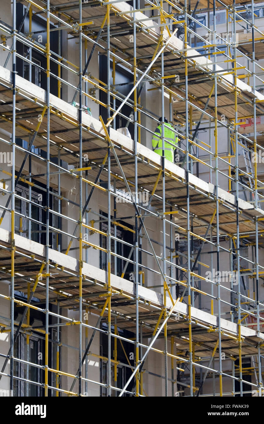 Workman walking along Scaffolding on a new building Stock Photo - Alamy