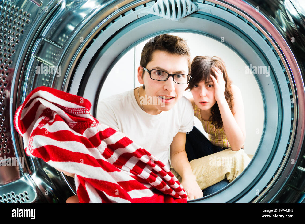 Funny couple loading clothes to washing machine Stock Photo - Alamy