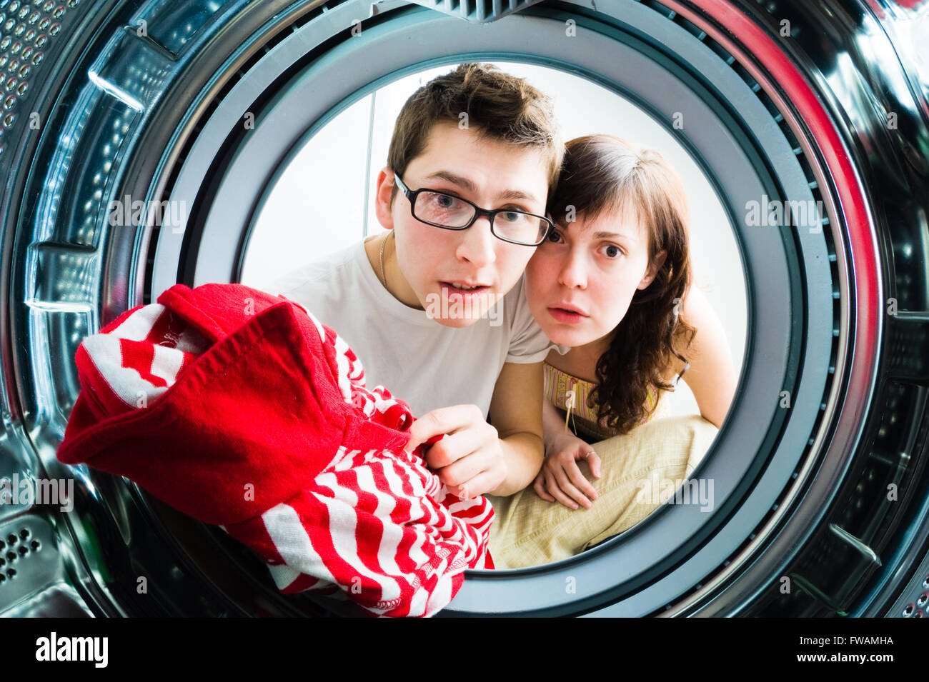 Funny couple loading clothes to washing machine Stock Photo - Alamy