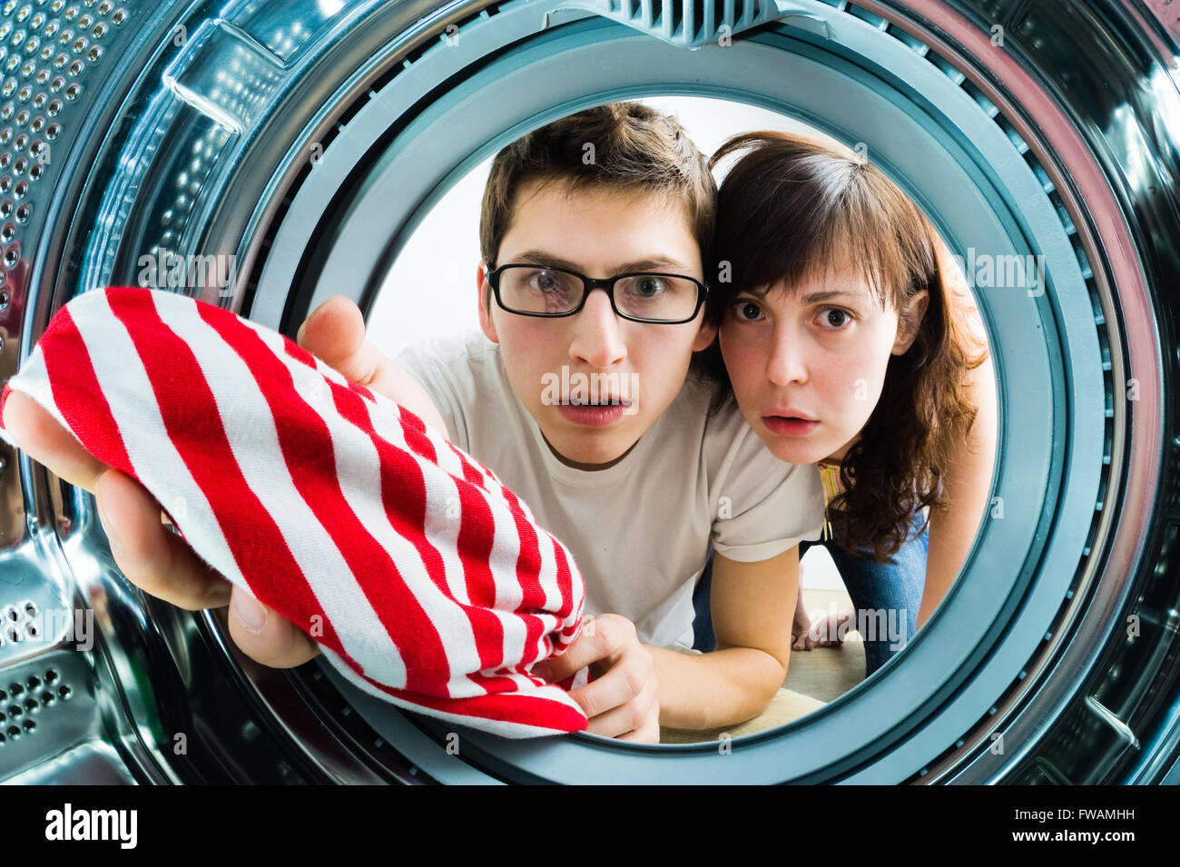 Funny couple loading clothes to washing machine Stock Photo - Alamy