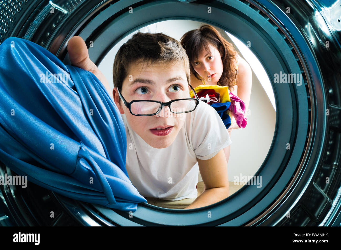 Funny couple loading clothes to washing machine Stock Photo - Alamy