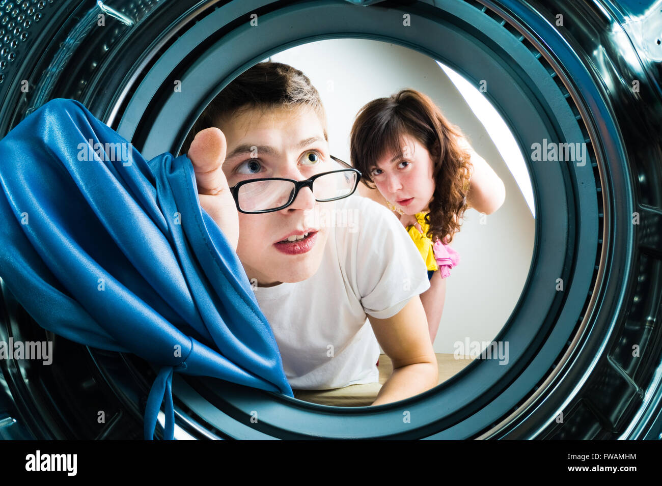 Funny couple loading clothes to washing machine Stock Photo - Alamy