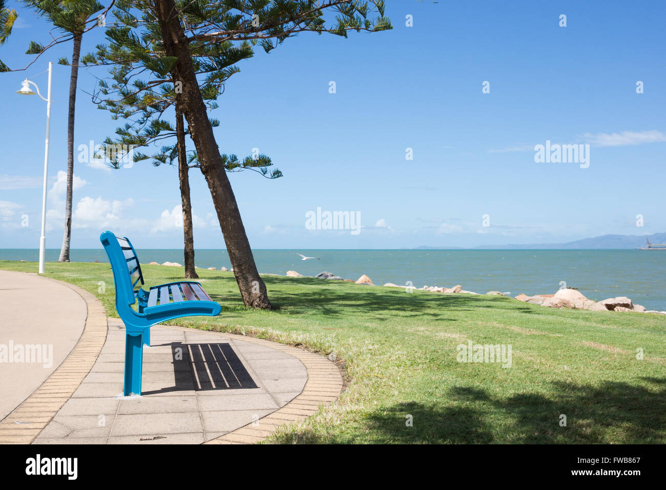 Blue park bench on The Strand beach, Townsville, Australia with sea ...