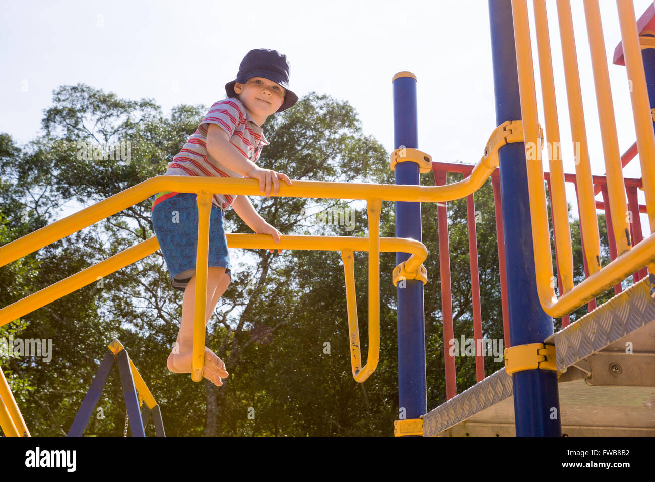 Young boy playing on climbing frame at playground Stock Photo - Alamy