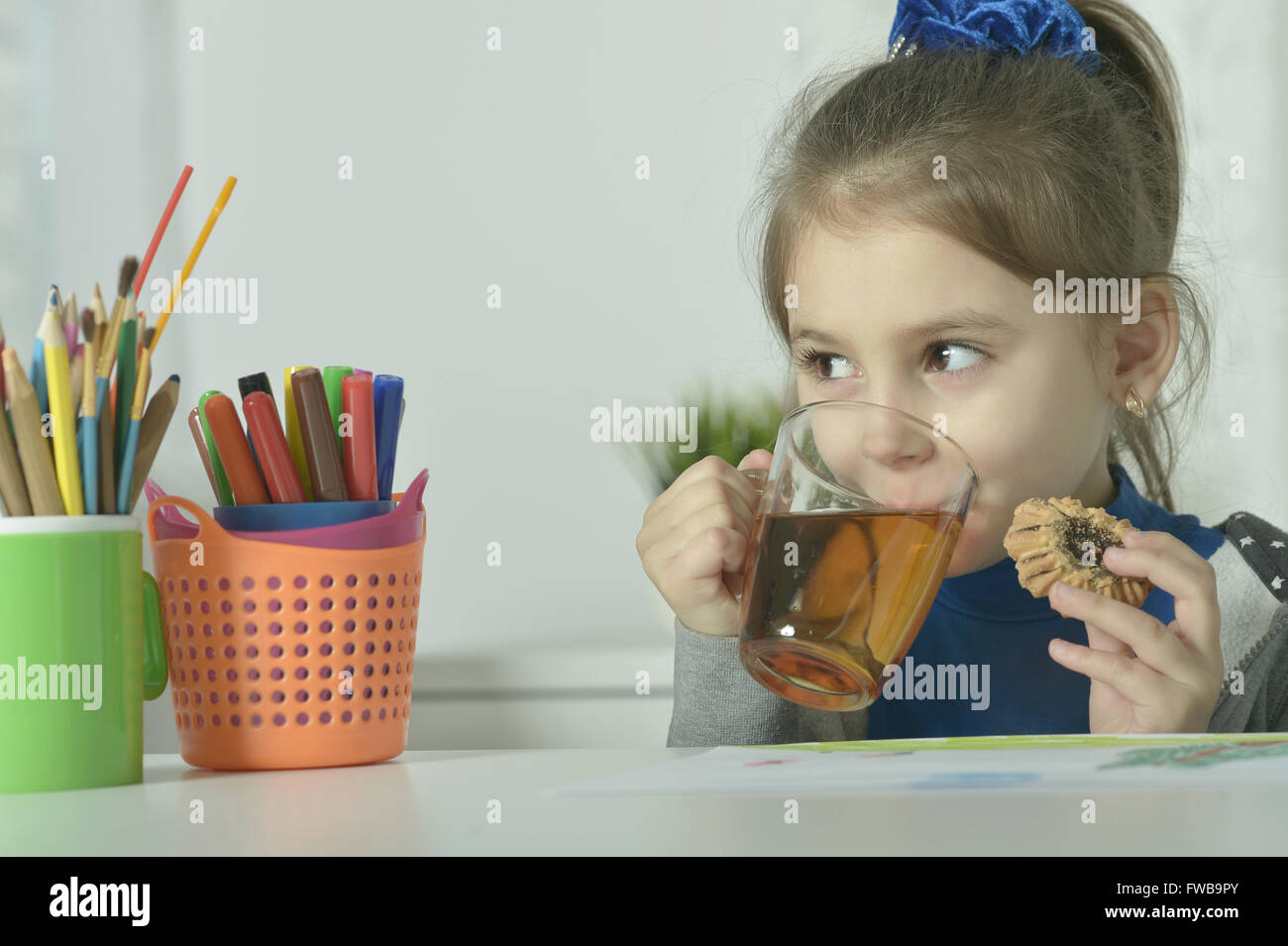 girl drinking tea and eating cookie Stock Photo - Alamy