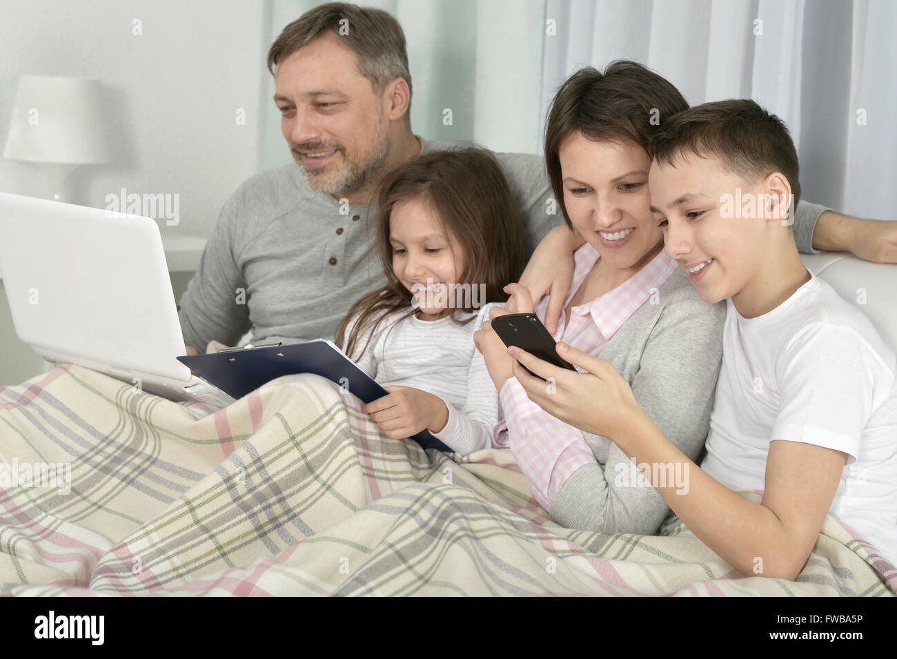 Family sitting with electronic gadgets Stock Photo - Alamy