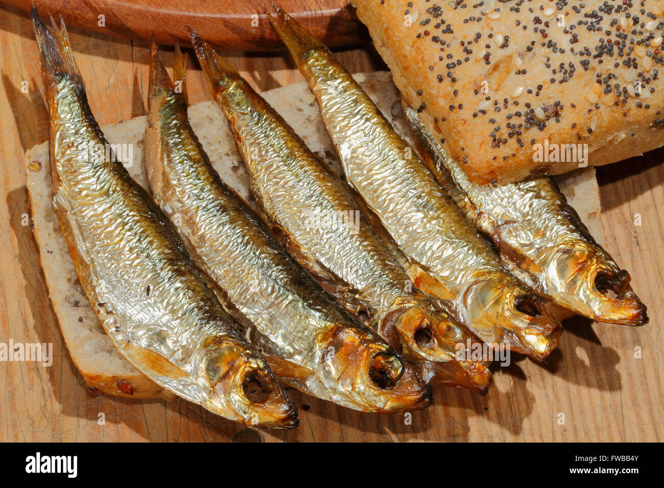 Smoked sprat in whole wheat bread, with lettuce on a wooden chopping ...