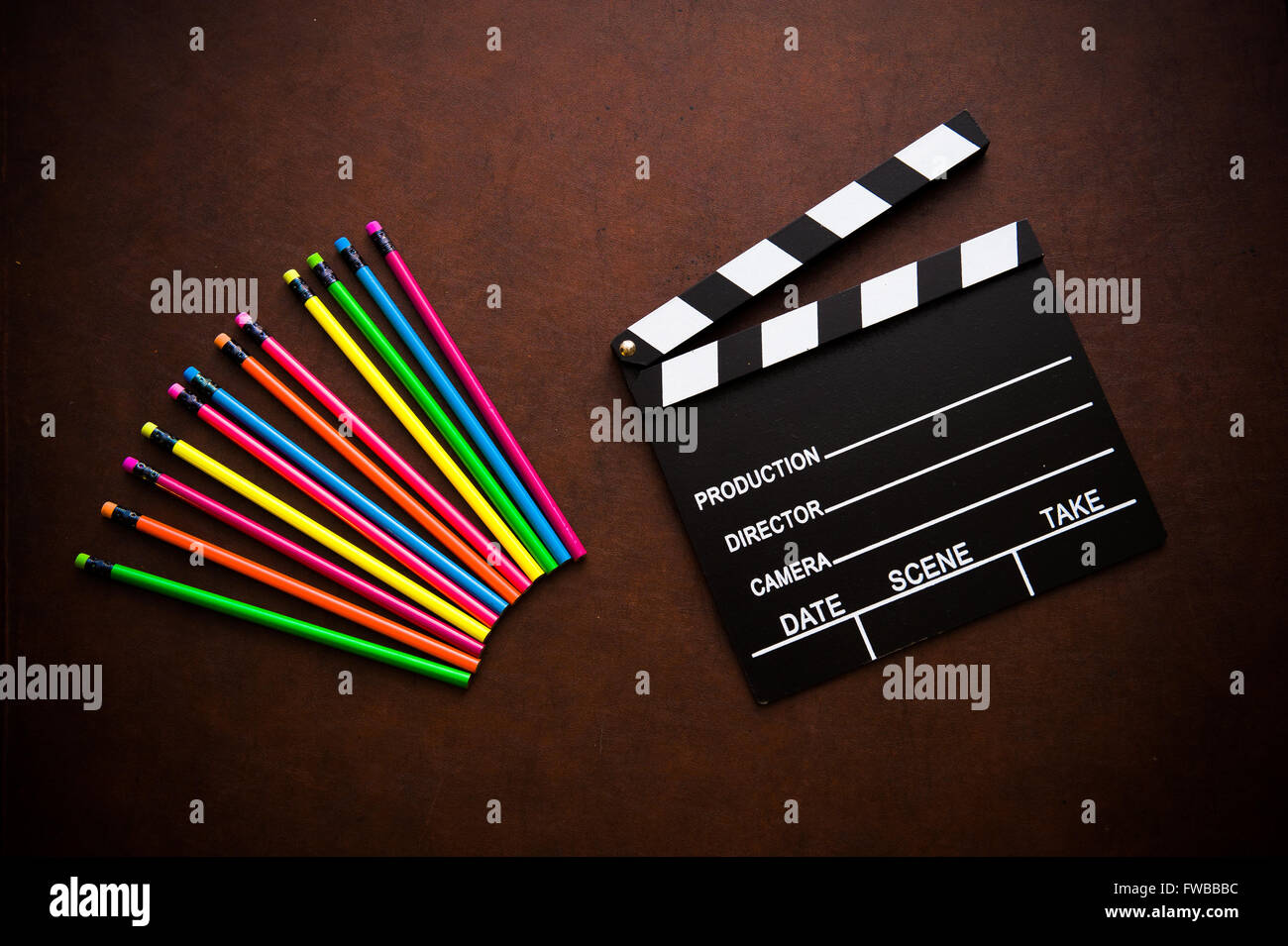 Wooden writer desktop with colorful pencil and black movie clapper ...
