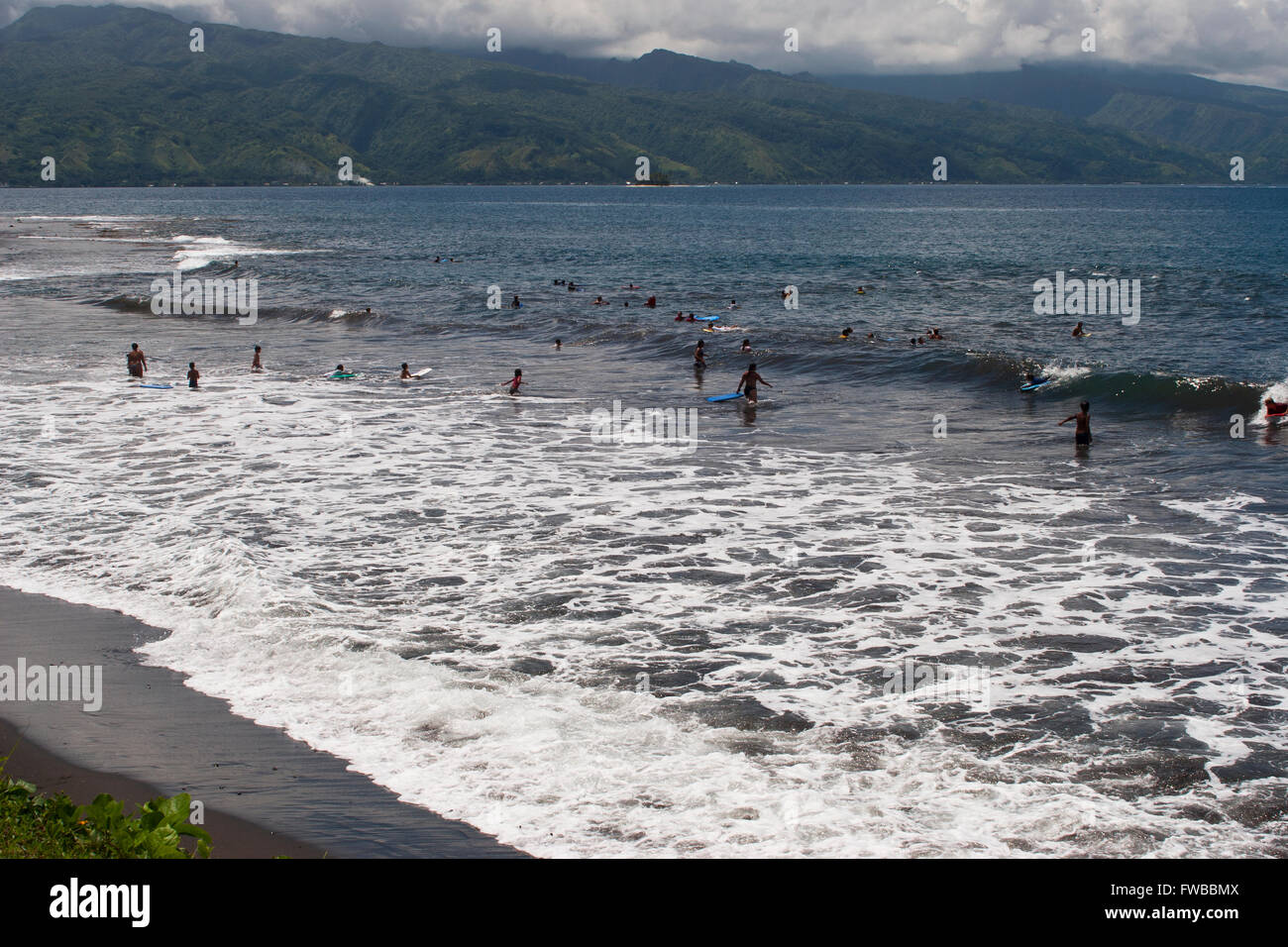Tahiti, French Polynesia, bathers in the surf at a beach on Tahiti ...