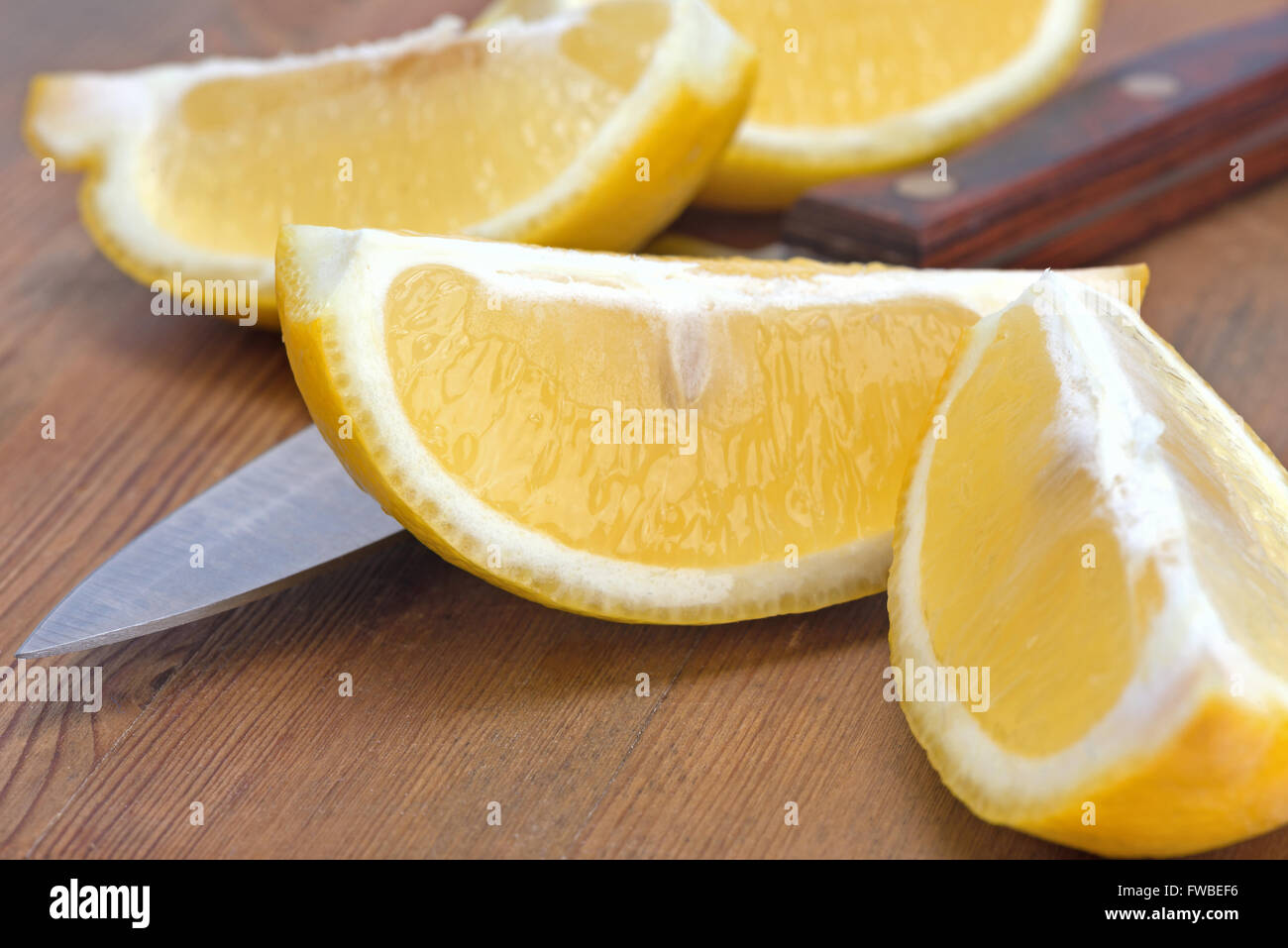 lemon cut into quarters and a knife on a wooden board Stock Photo - Alamy