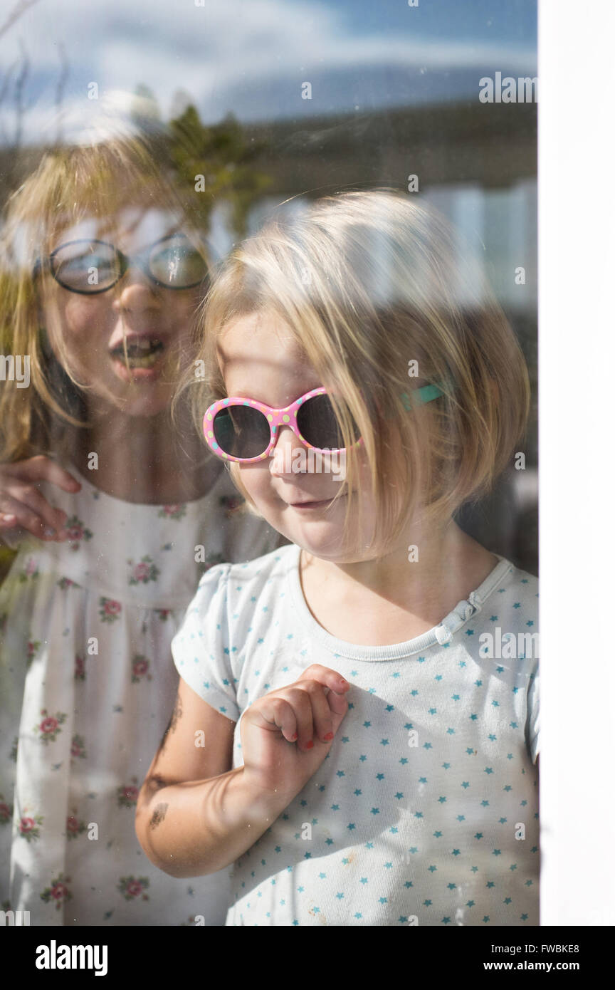 Girls looking through a window Stock Photo - Alamy