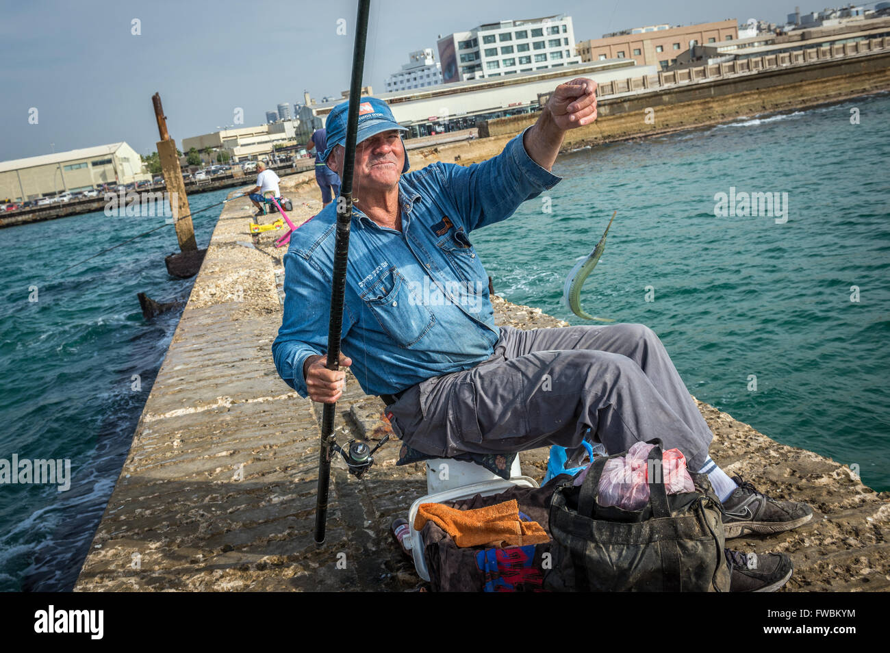 Man fishing on a breakwater in Tel Aviv Port neighbourhood, Tel Aviv ...