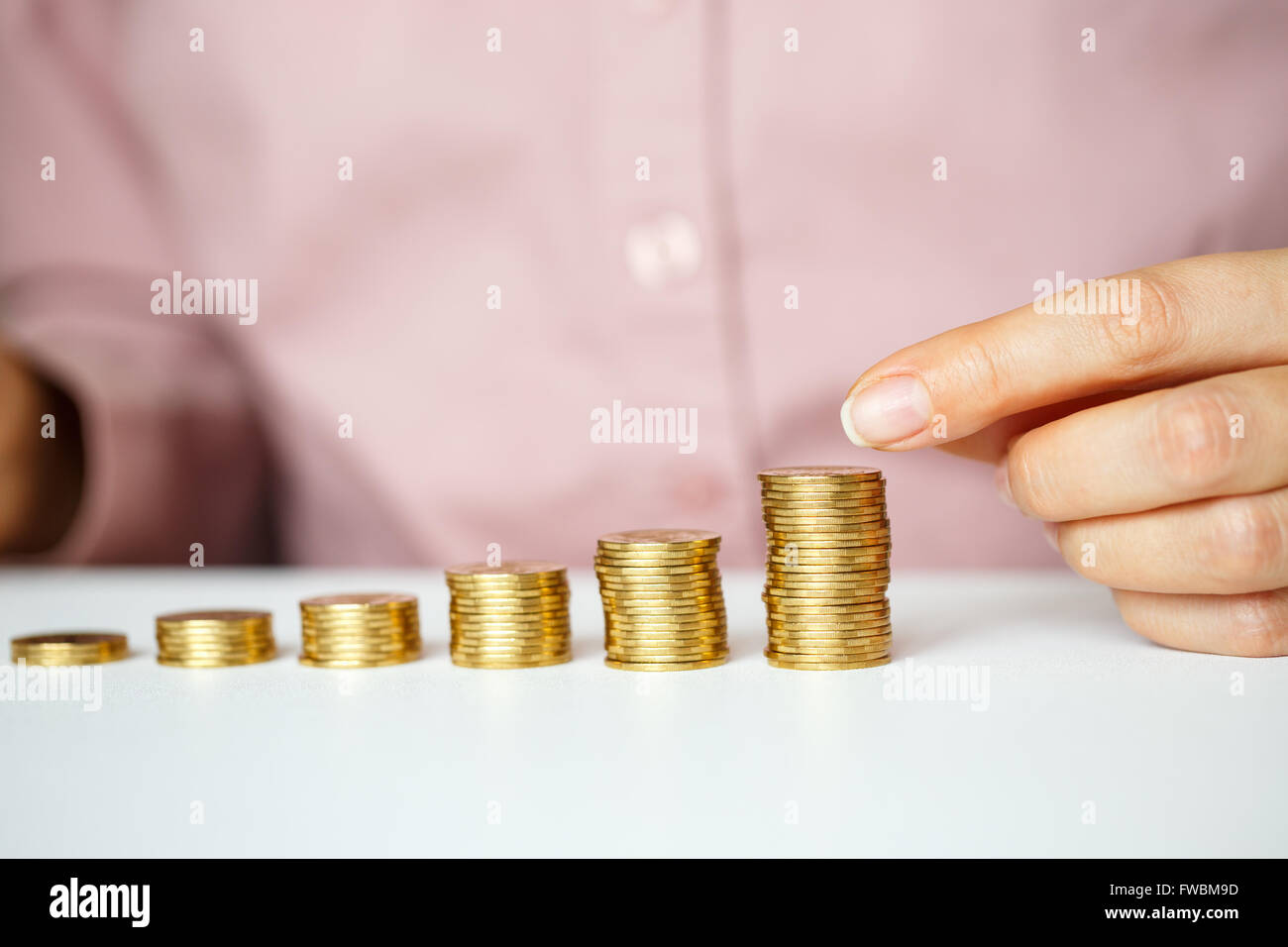 Savings, female hand stacking gold coins into increasing columns Stock ...