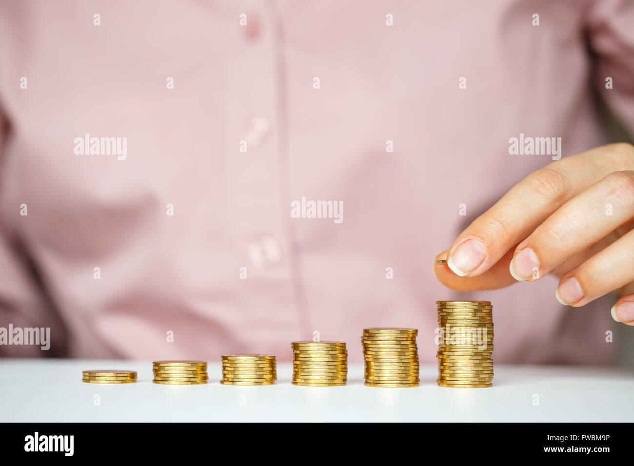 Savings, female hand stacking gold coins into increasing columns Stock ...