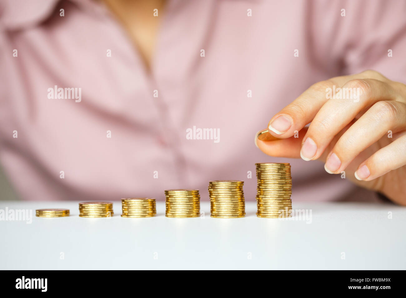 Savings, female hand stacking gold coins into increasing columns Stock ...