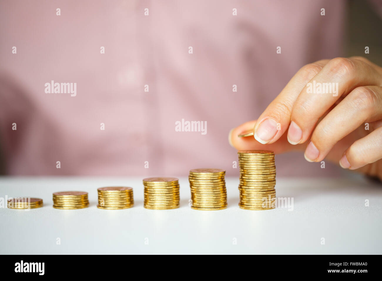 Savings, female hand stacking gold coins into increasing columns Stock ...