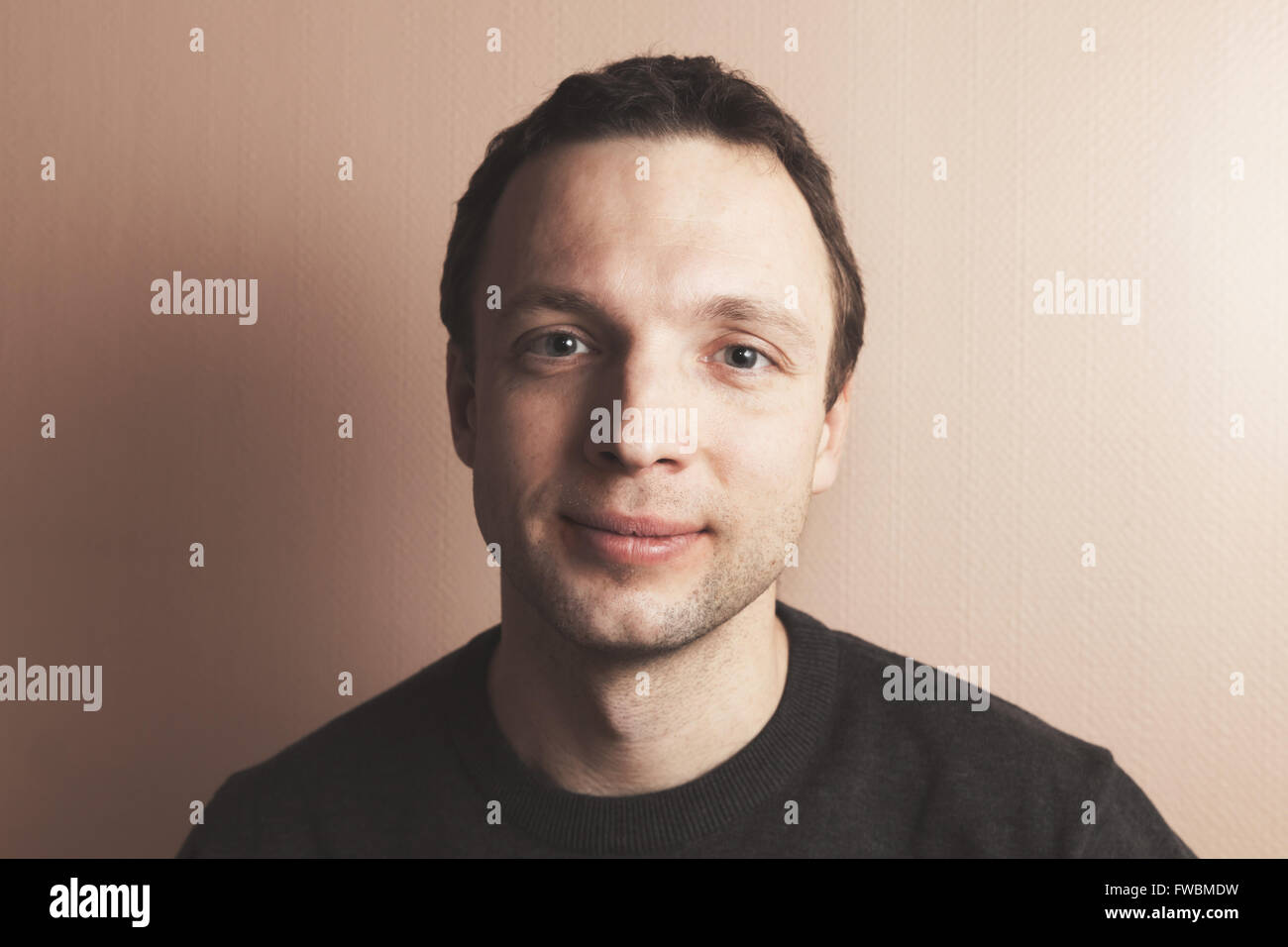 Young handsome positive Caucasian man studio portrait over gray wall ...