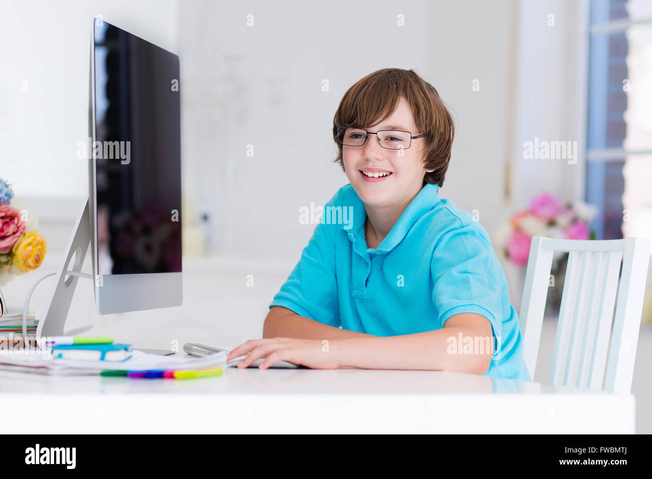 School boy working on personal computer at home. Student doing homework ...