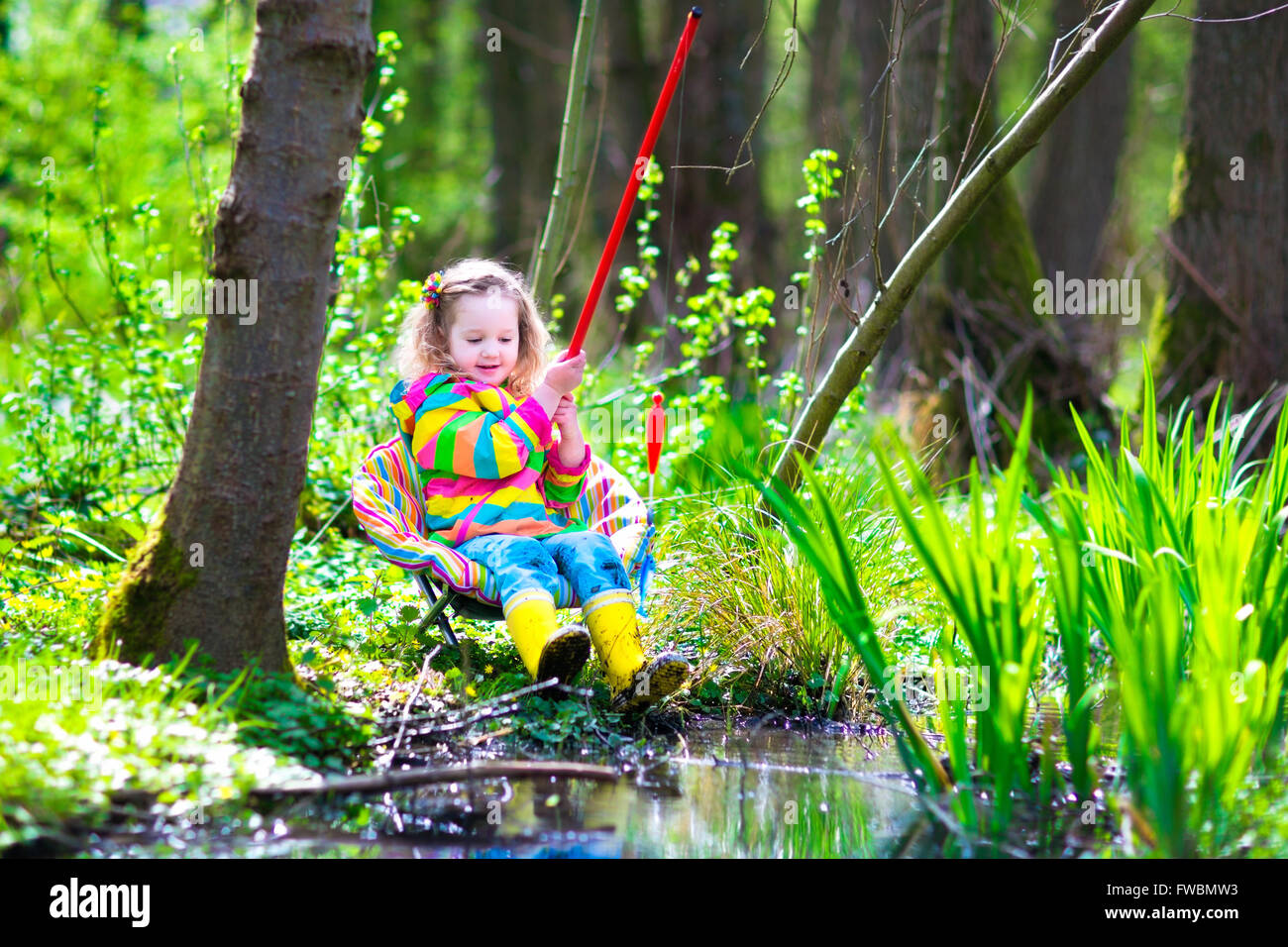 Child playing outdoors. Preschooler kid catching fish with red rod ...