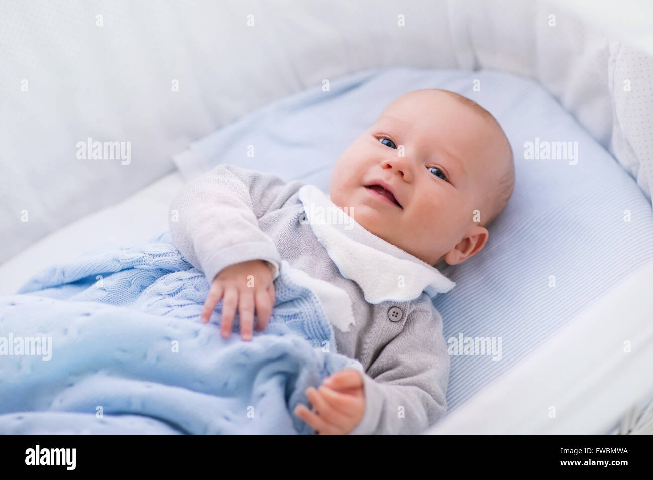 Funny baby in white crib with canopy. Nursery interior and bedding for ...