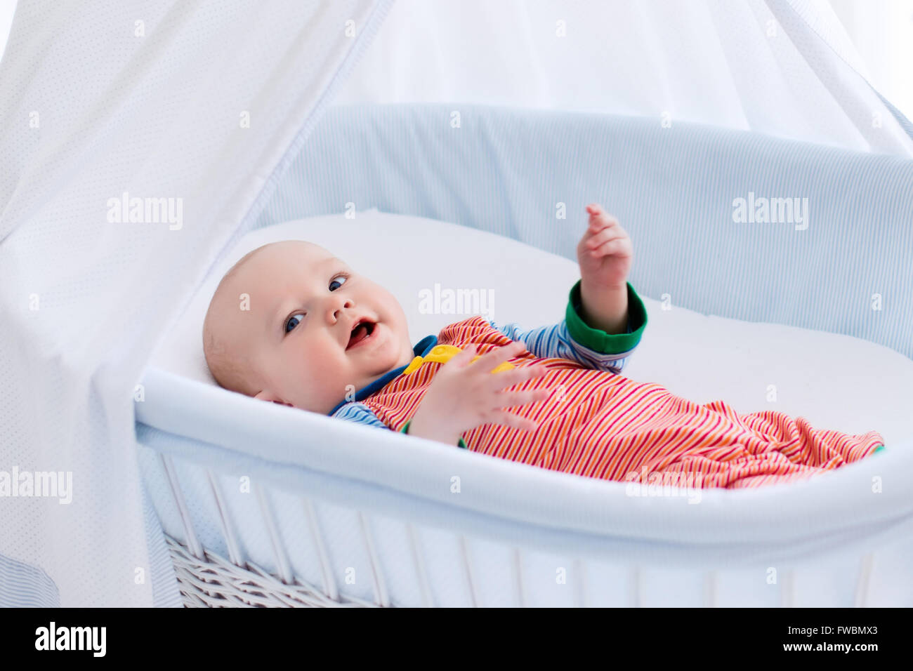 Funny baby in white crib with canopy. Nursery interior and bedding for ...