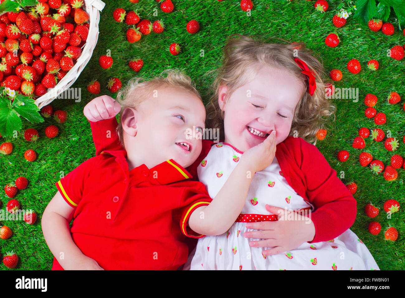 Child eating strawberry. Little girl and baby boy play and eat fresh ...