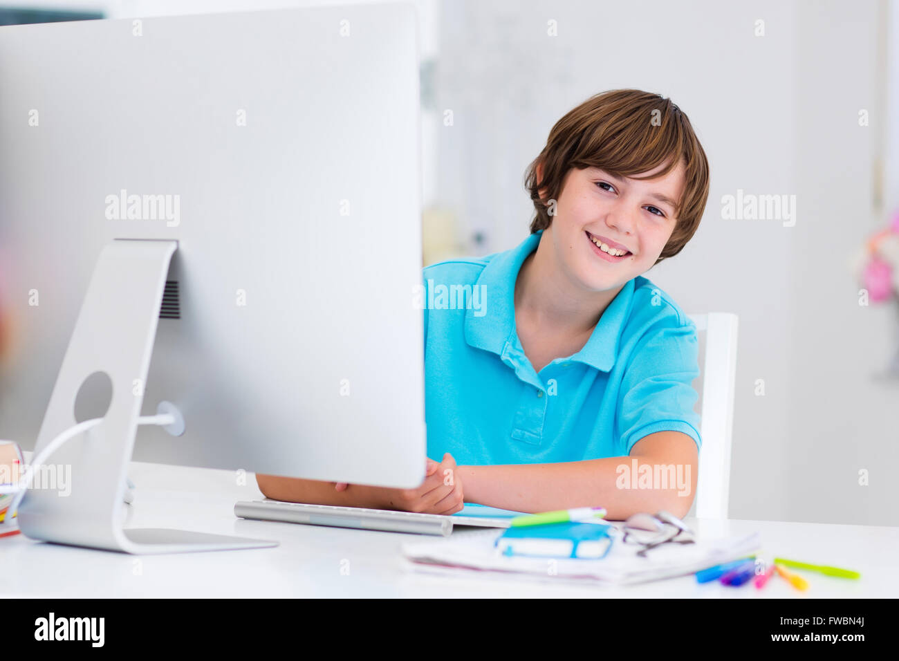 School boy working on personal computer at home. Student doing homework ...
