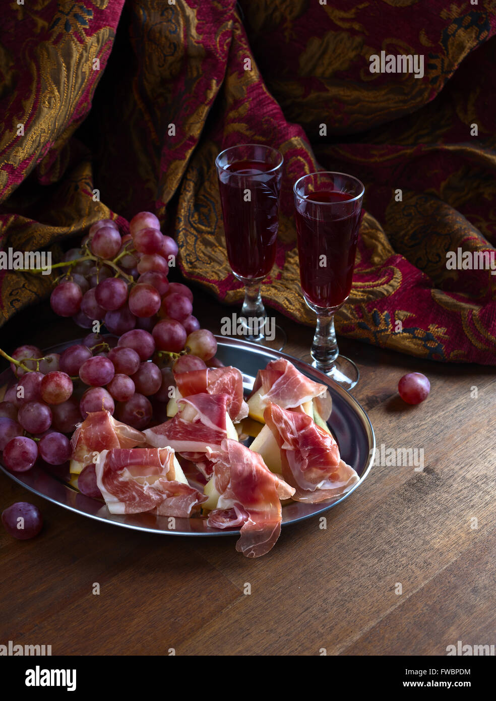 Spanish jamon with melon and grape on wooden table Stock Photo - Alamy