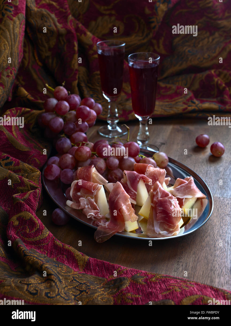 Spanish jamon with melon and grape on wooden table Stock Photo - Alamy