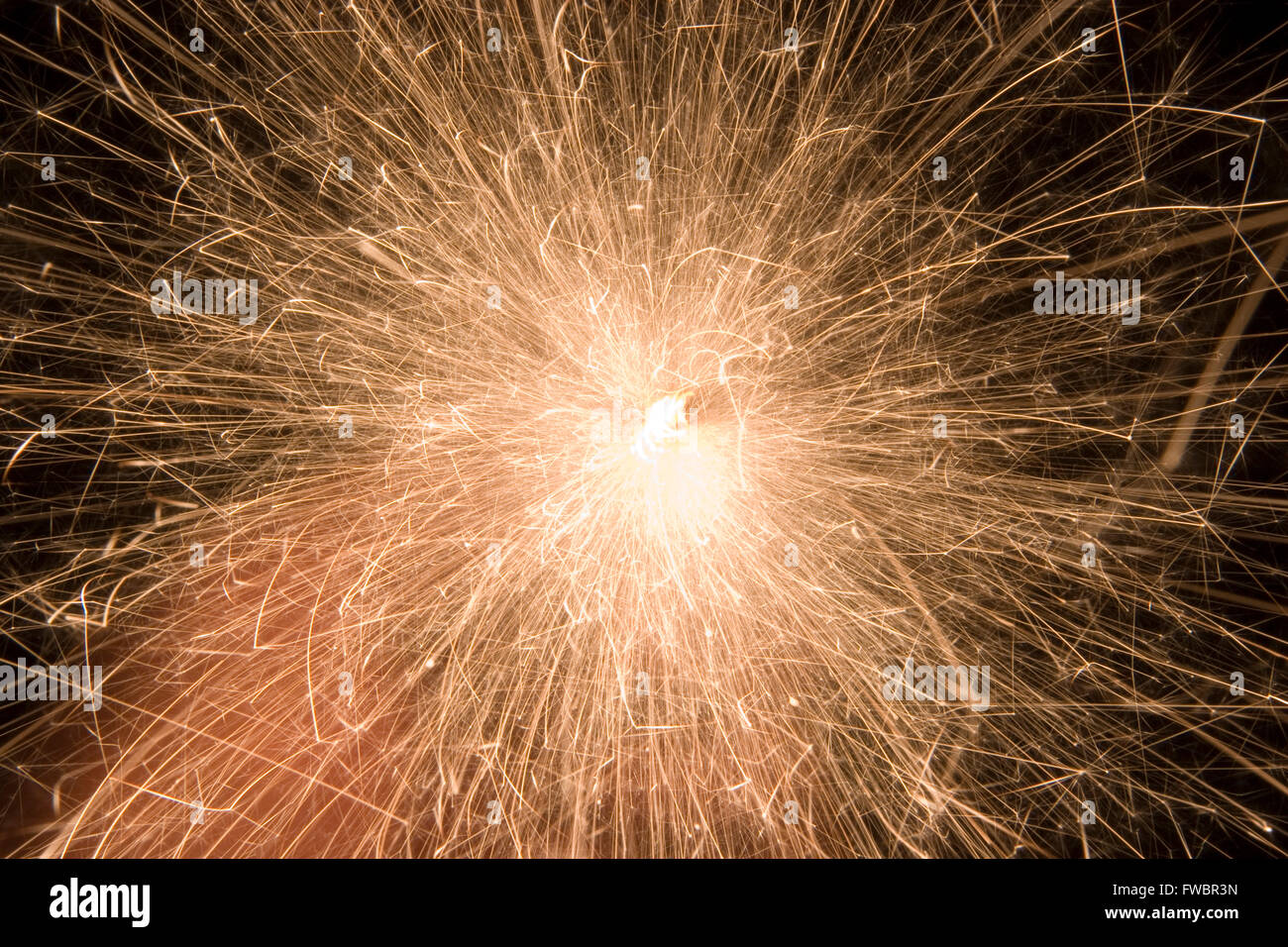 Sparks from a sparkler radiate outwards from the central core of the ...
